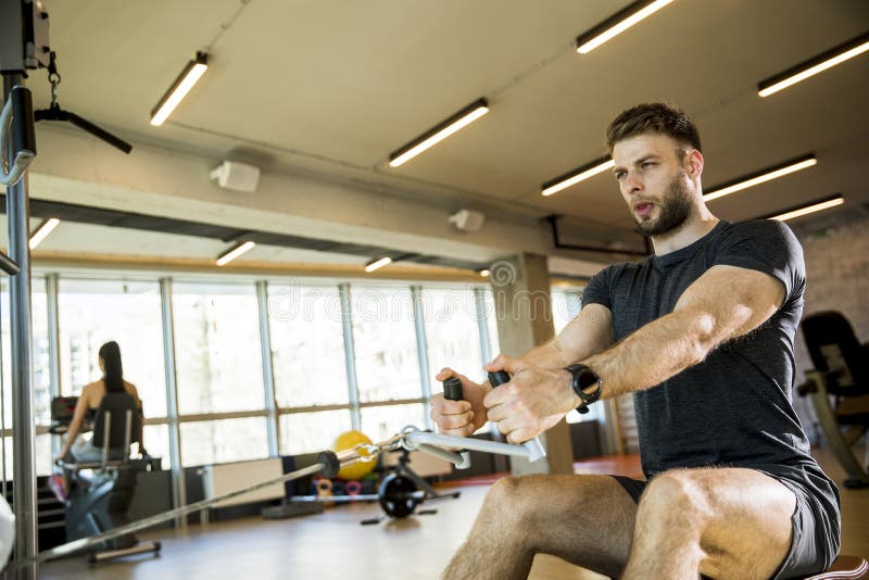 Young Man Using Seated Row Machine in the Gym Stock Photo - Image of ...
