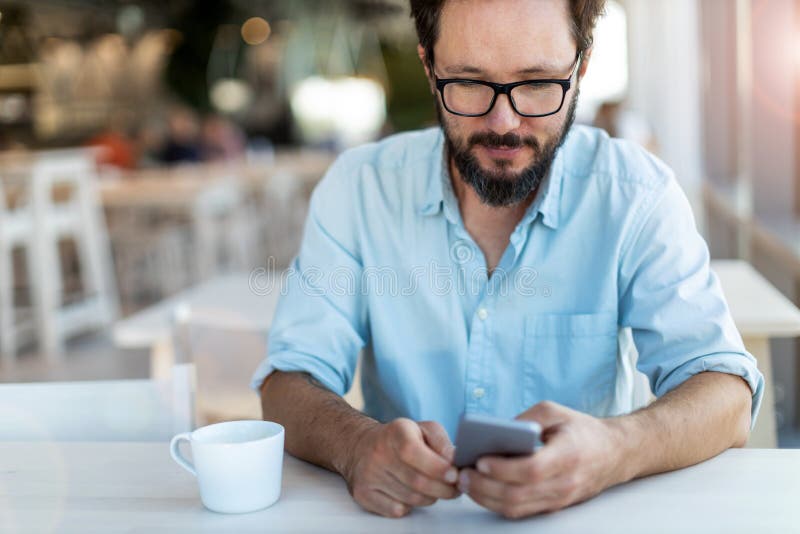 Young Man Using Smartphone in a Cafe Stock Image - Image of ...