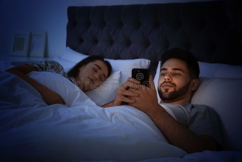 Young Man Using Smartphone while His Girlfriend Sleeping in Bed Stock ...