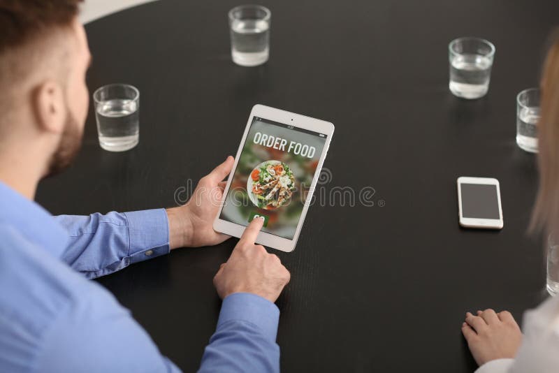 Young Man Using Tablet Computer for Ordering Food in Office Stock Photo ...