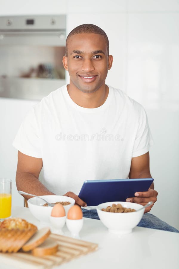 Young Man Using Tablet and Eating Breakfast in Kitchen Stock Image ...