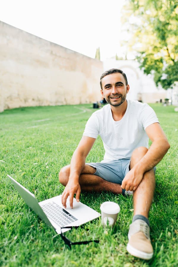 Young Handsome Man Using and Typing Laptop Computer in Summer Grass ...