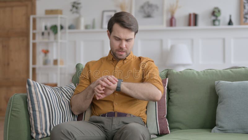 Young Man Waiting while Checking Watch on Sofa Stock Photo - Image of ...