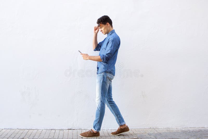Young Man Walking and Reading Text Message on Cell Phone Stock Image ...