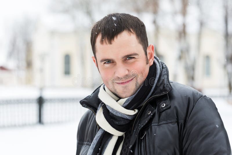 Young Man in Warm Coat Smiling at Camera on Blurred Background of Snowy ... Young Man in Warm Coat Smiling at Camera on Blurred Background of Snowy ...