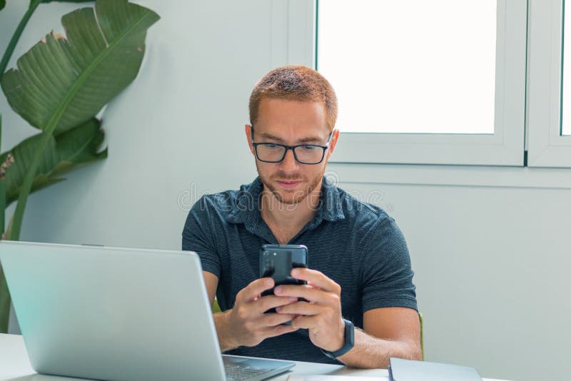 Young Man Watching Mobile and Smiling in Work Environment Stock Image ...