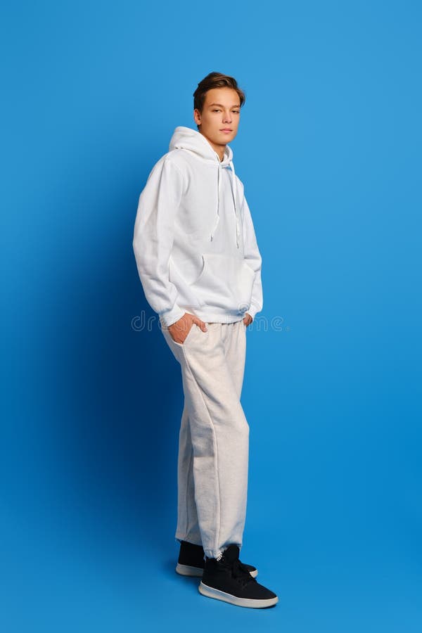 Young Man Wearing White Sweatshirt and Sweatpants Standing Over Blue ...