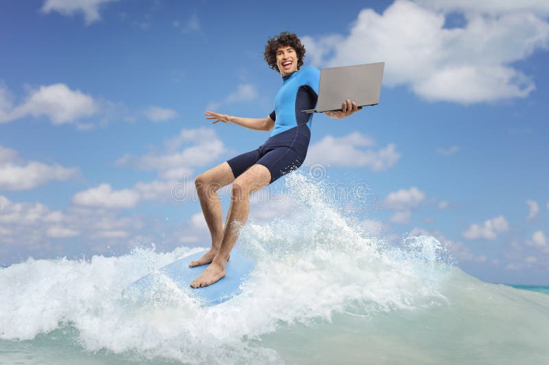 Young Man in a Wetsuit Riding a Surfboard with a Laptop Stock Image ...