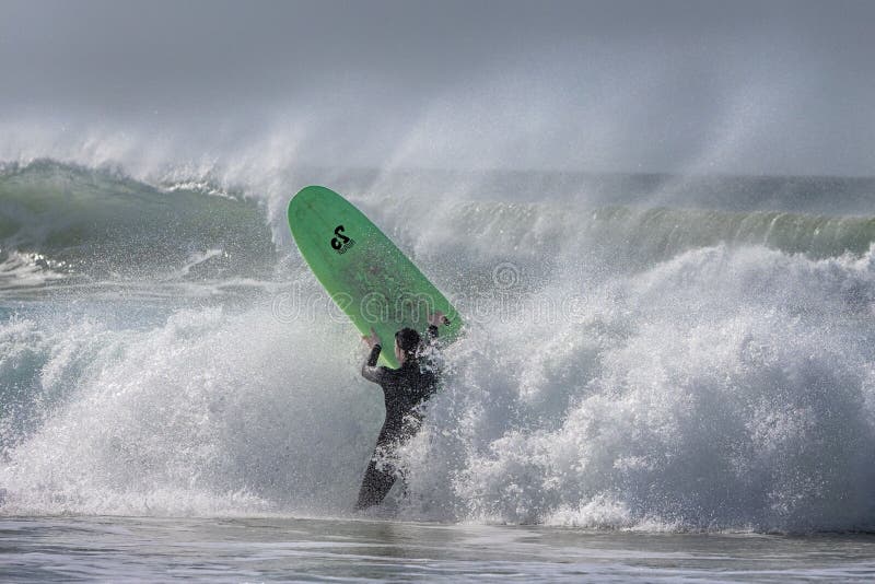 Young Man in a Wetsuit Riding a Surfboard, Standing Atop a Large Wave ...