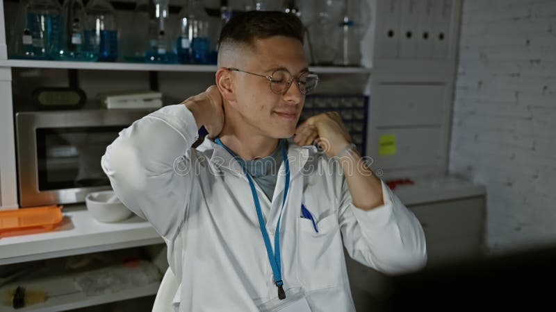 A Young Man in a White Lab Coat Stretches His Neck in Relief Inside a ...