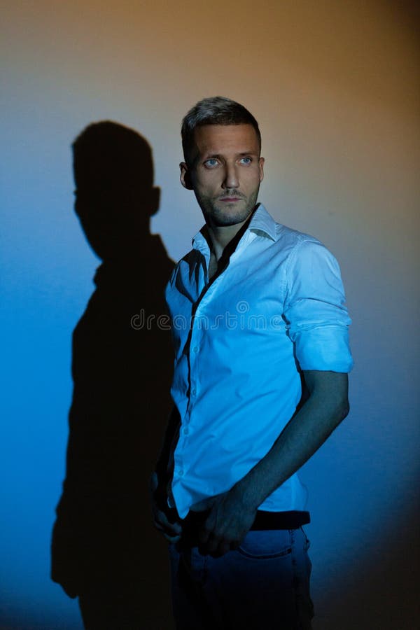 A Young Man in a White Shirt Looks To the Side in Colored Lighting ...