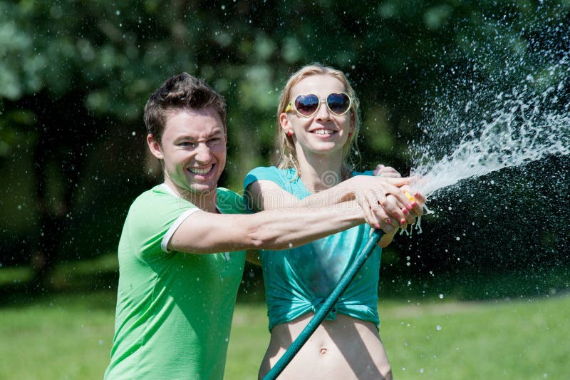 Young Man and Woman Playing with Water Spray Stock Image - Image of ...