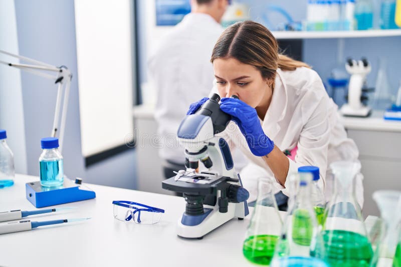 Young Man and Woman Scientists Workers Using Microscope at Laboratory ...