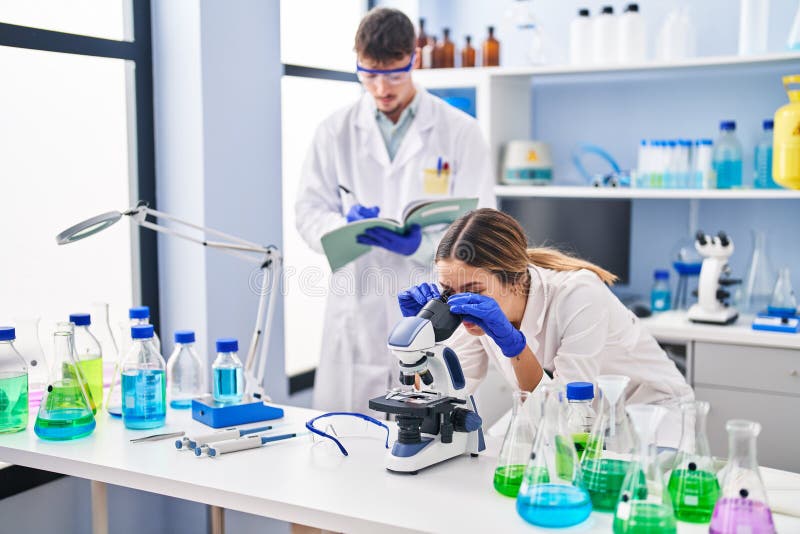 Young Man and Woman Scientists Workers Using Microscope at Laboratory ...