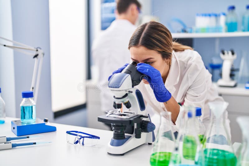 Young Man and Woman Scientists Workers Using Microscope at Laboratory ...