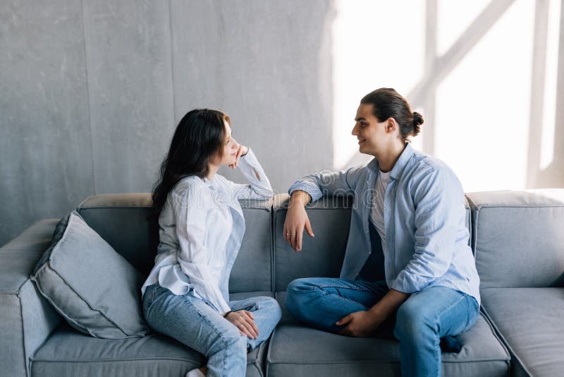 Young Man and Young Woman Sitting on a Couch and Talk Stock Image ...