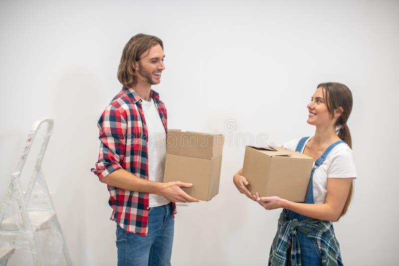 Young Man and Woman Standing Near the Wall with Boxes in Hands Stock ...