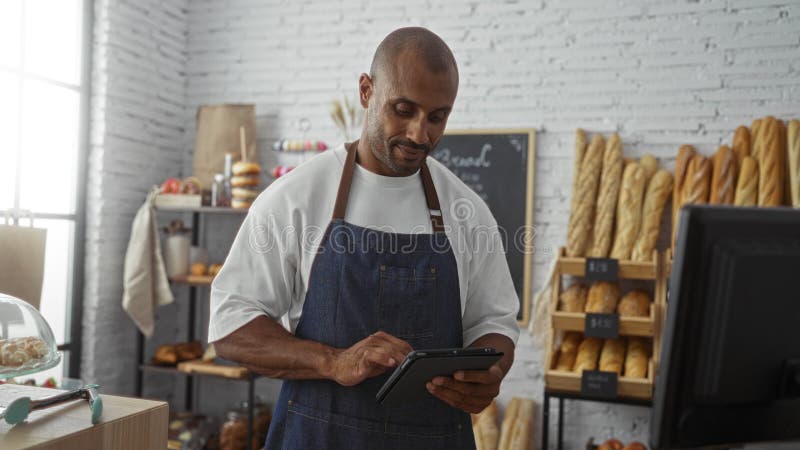 Young Man Working in a Bakery Using a Tablet Surrounded by Various ...