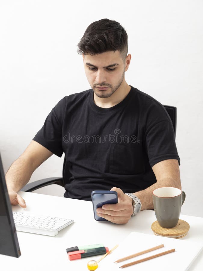 Young Man Working and Checking His Smart Phone in His Home Office Stock ...