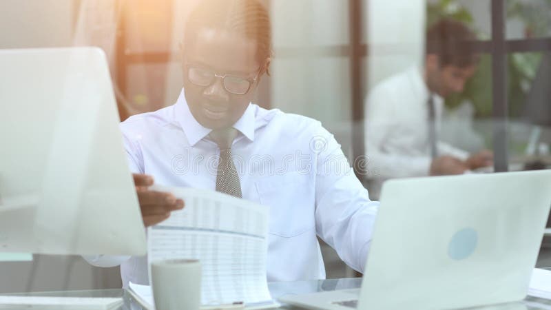 Young Man Working at a Computer Against the Backdrop of a Light Office ...