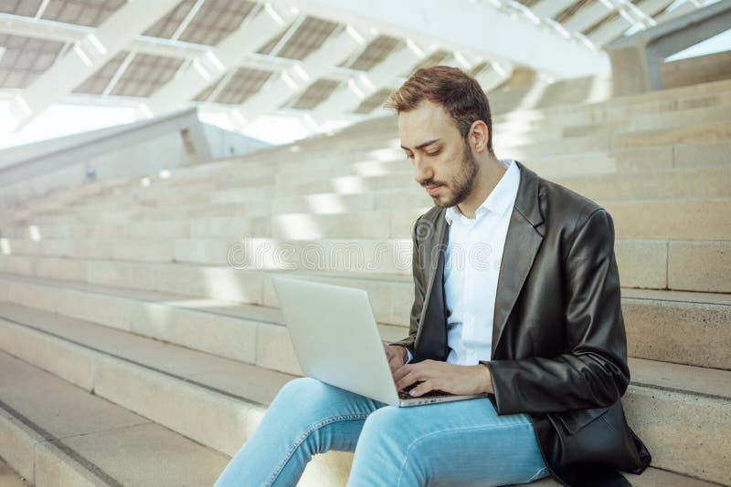 Young Man Working at a Computer Sitting on a Staircase Outside Stock ...