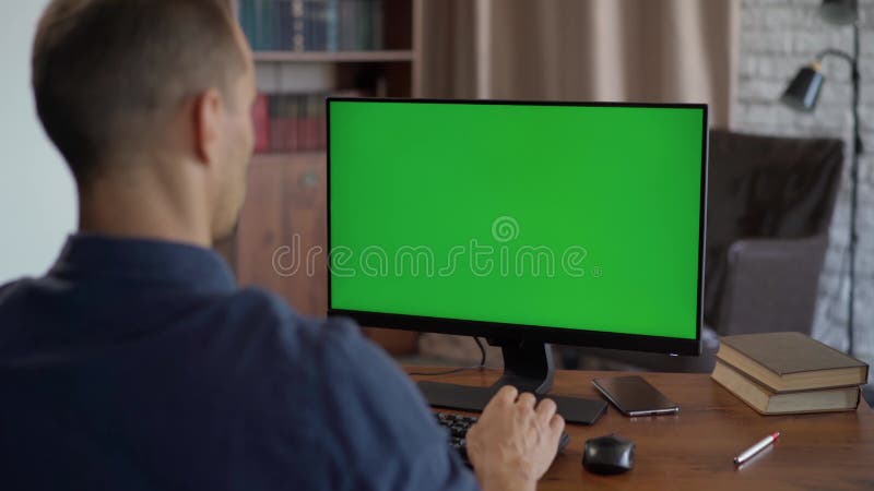 Man Working at Desk Using Computer with Green Mock-up Screen in Cozy ...