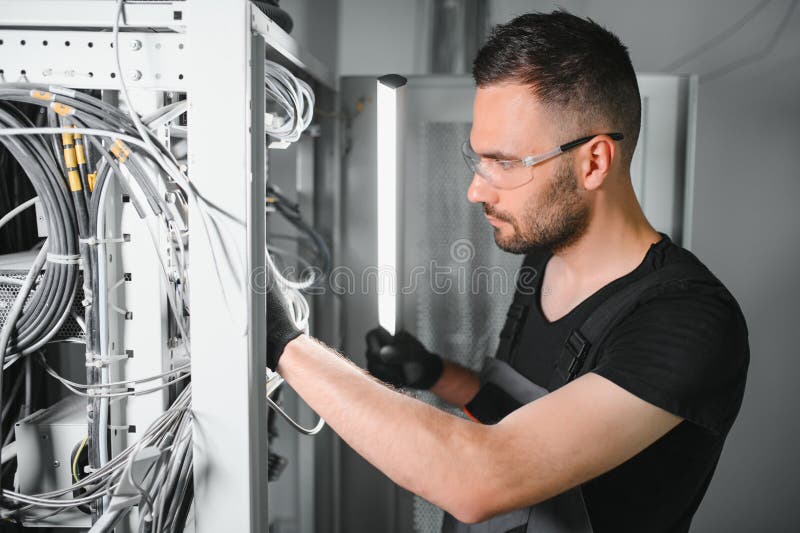 Young Man is Working with Internet Equipment and Wires in Server Room ...