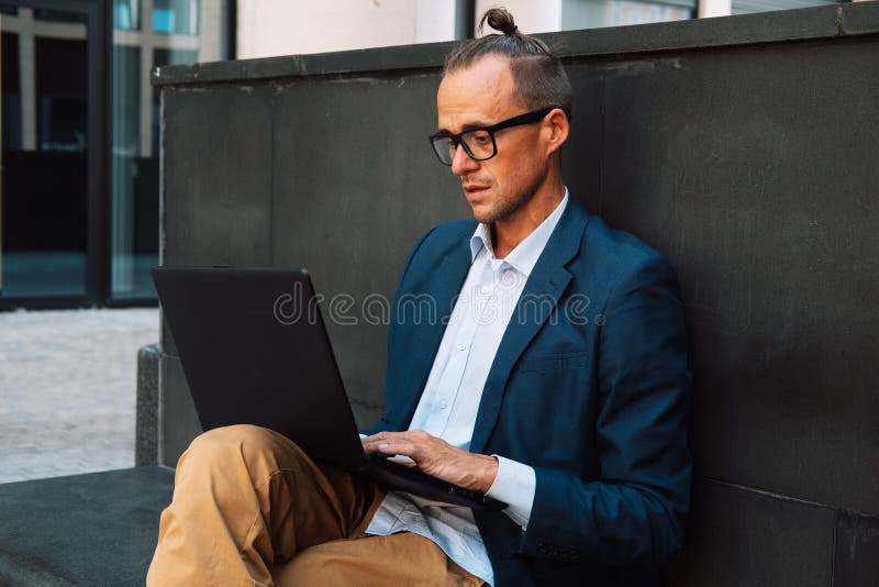 Young Man Working on Laptop Computer while Sitting on Bench Outdoors ...