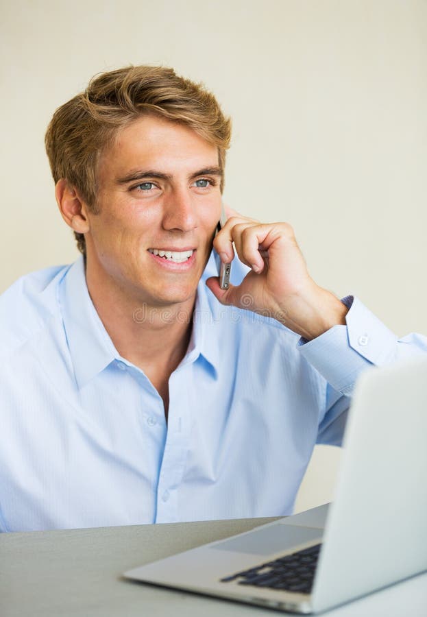 Young Man Working on Laptop Computer Talking on Phone Stock Photo ...