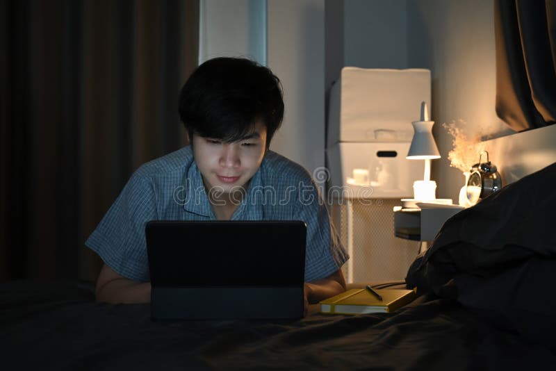 Man Working at Night with Computer Tablet on His Bed. Stock Photo ...