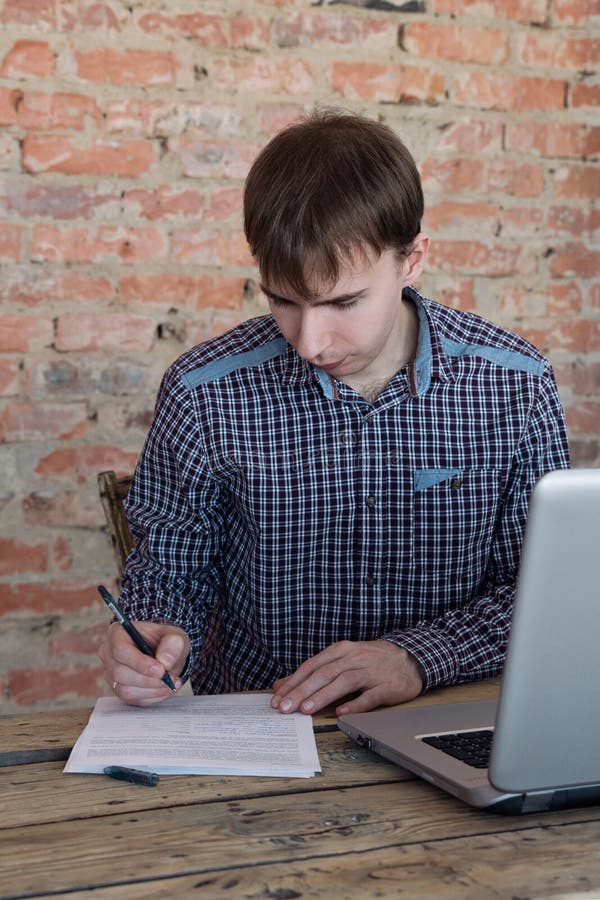 Young Man Working in Office, Sitting at Desk, Writing Stock Photo ...