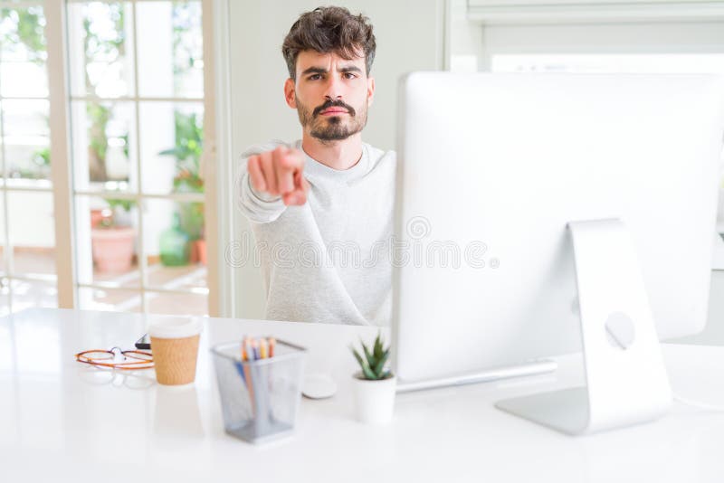 Young Man Working Using Computer Pointing with Finger To the Camera and ...
