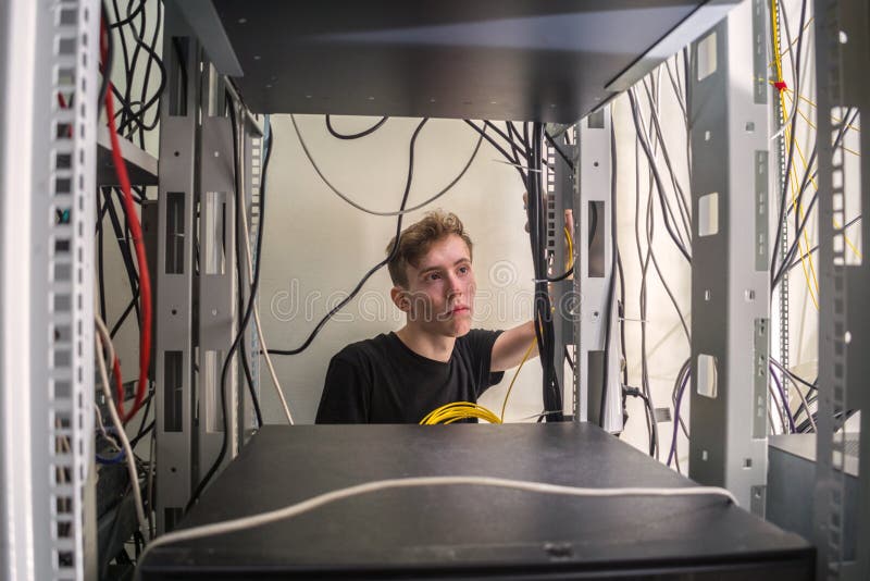 A Young Man Works Inside a Server Rack. a Technician Switches ...