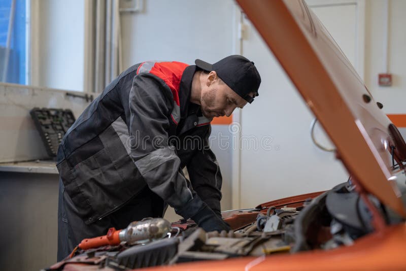Young Man in Workwear Bending Over Open Car Hood with Engine Stock ...