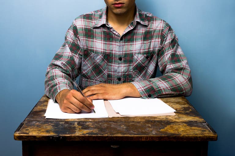 Young man writing at desk stock image. Image of seated - 32977271