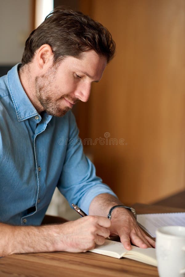 Young Man Writing in a Notebook while Working from Home Stock Photo ...