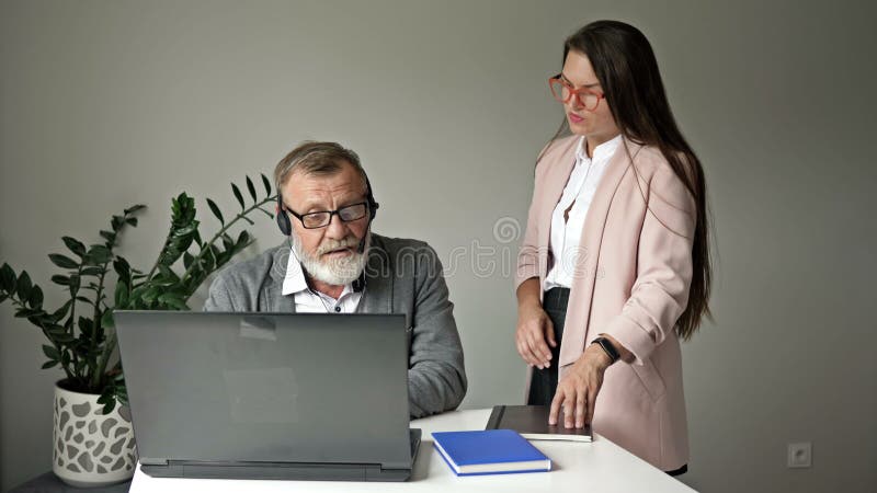 Young Manager Helps a Senior Employee with Computer Work in the Office ...