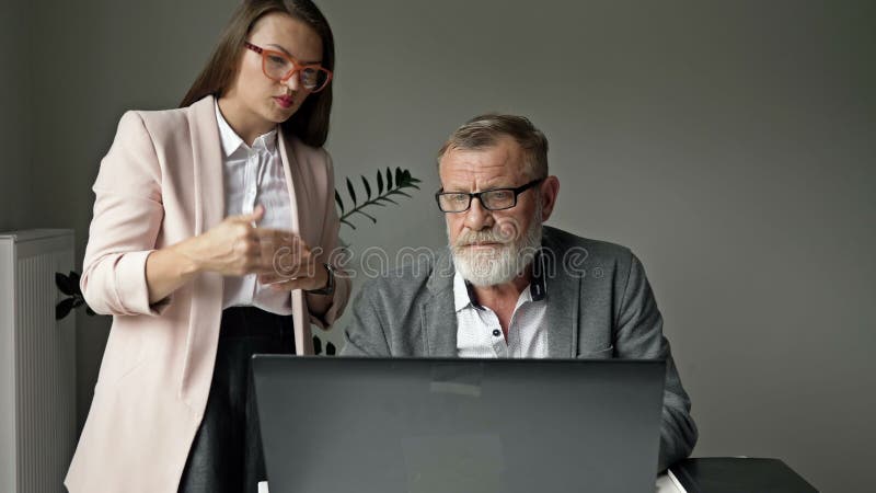 Young Manager Helps a Senior Employee with Computer Work in the Office ...