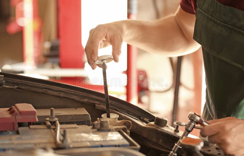 Young Mechanic Checking Engine Oil Level in Car Service Center Stock ...
