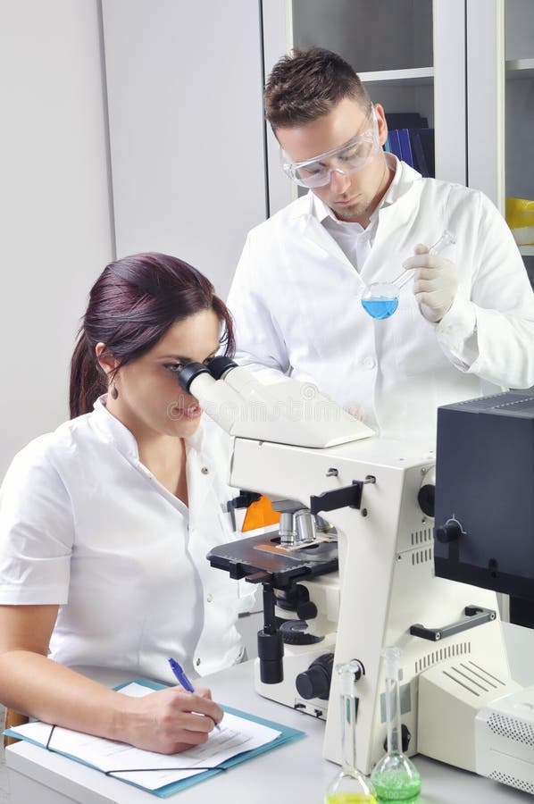 Young Medical Scientists Studying New Substance or Virus in Microscope ...