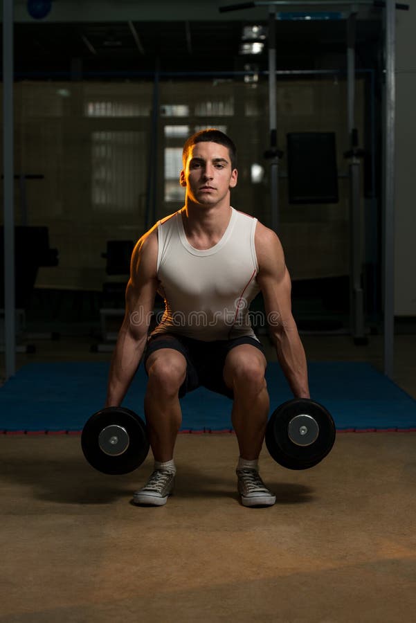 Young Men Doing Squats with Dumbbell in Gym Stock Photo - Image of ...