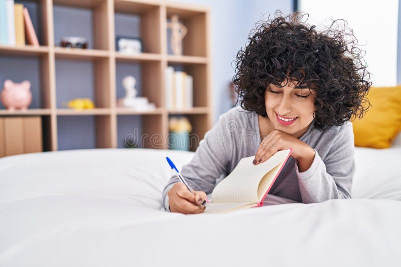 Young Middle East Woman Writing on Notebook Lying on Bed at Bedroom ...