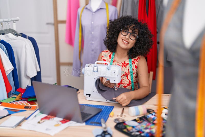 Young Middle Eastern Woman Tailor Using Sewing Machine and Laptop at ...
