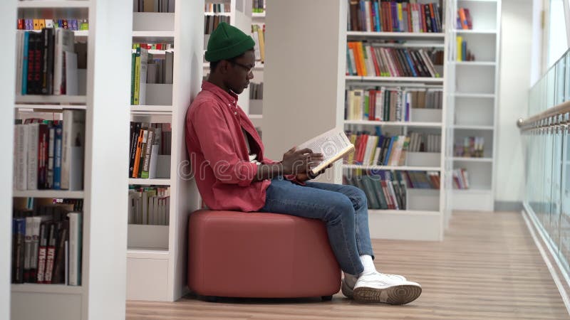 Young Millennial African Guy Reading Book In Bookstore Spending Time