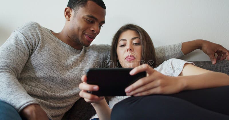 Young Millennial Couple Laughing At A Cute Pictures On Social Media