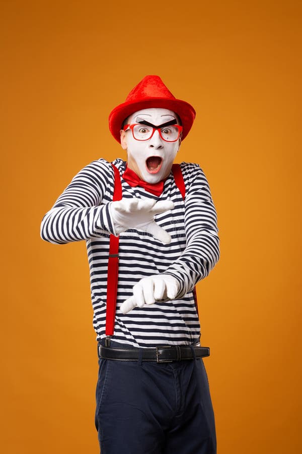 Young Mime Man Looking at Camera in Vest and Red Hat Isolated on Orange ...