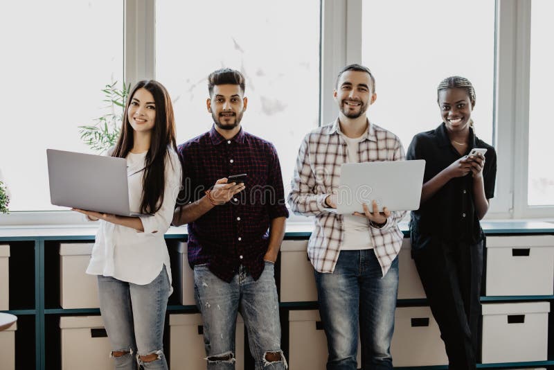 Young Mixed Race Team Standing with Devices in Modern Office Stock ...
