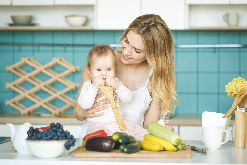 Young Mother is Cooking and Playing with Her Baby Daughter in a Kitchen ...