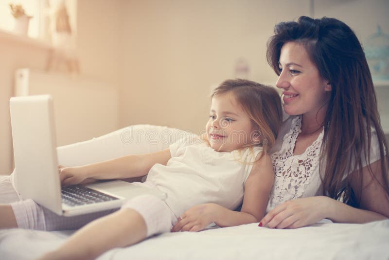 Young Mother with Daughter Using Laptop on Bed at Home. Stock Photo ...