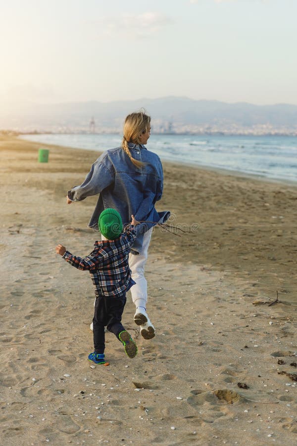 Young Mother and Her Toddler Son Playing Tag on the Beach at Sunset ...